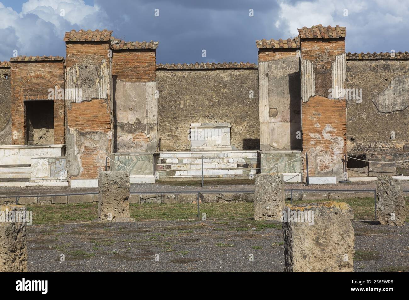 Remnants of old stone columns and terracotta brick and stone walls in a courtyard at the ancient ...