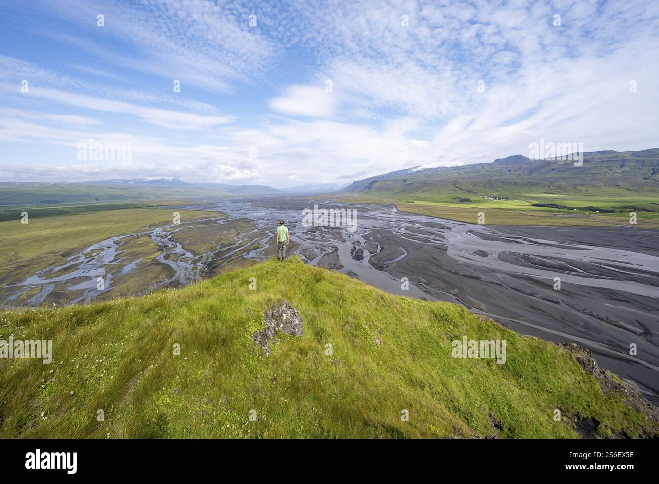 Hiker, young man on a hill, view over alluvial land, meandering river ...