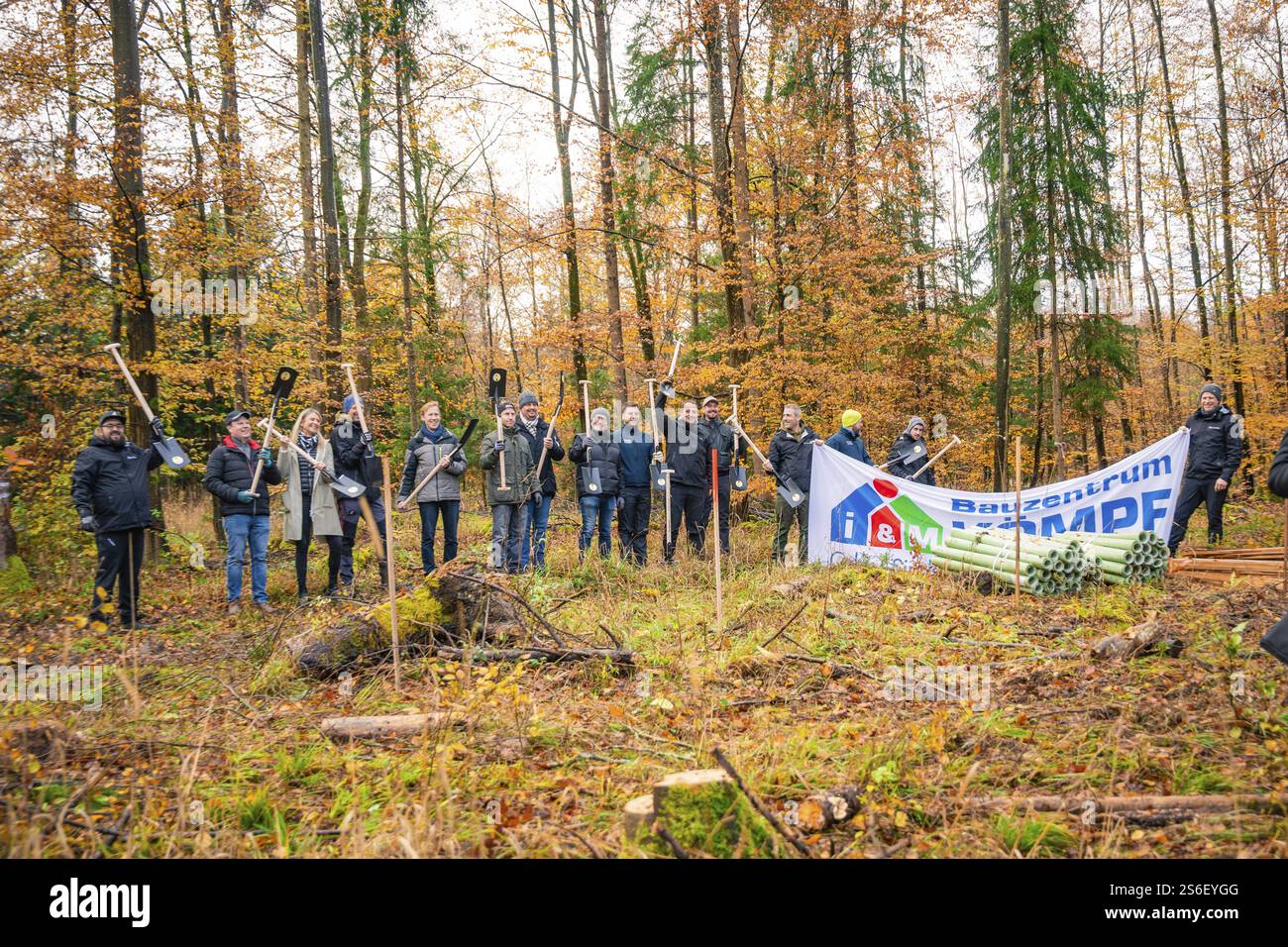 Group posing for a photo with a banner in autumn forest, tree planting ...