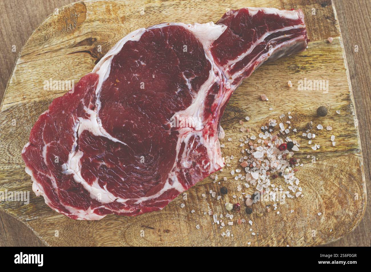 Raw rib eye steak, cowboy steak, on a wooden chopping board, top view ...