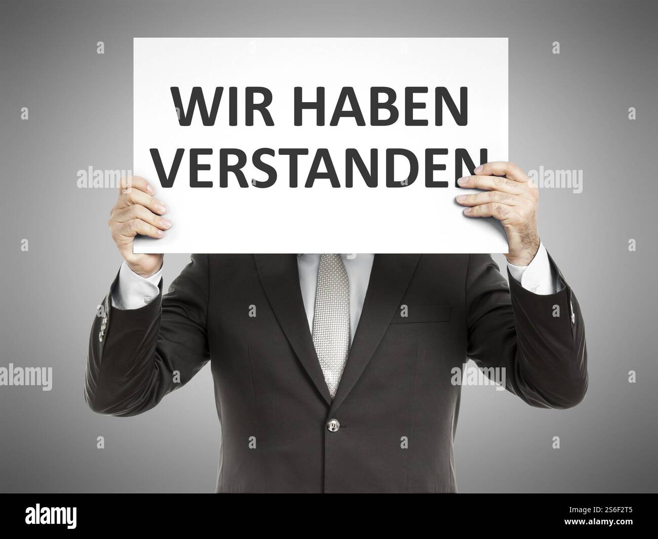 A business man holding a paper in front of his face with the message we ...