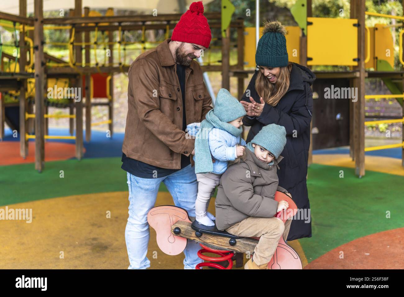 Parents watching their children joyfully riding a spring rider on a ...