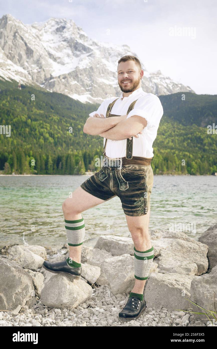 A traditional bavarian man at lake Eibsee with the Zugspitze mountain ...
