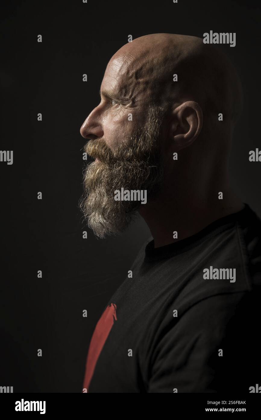 An image of a bearded man with a bald head side view and dark ...