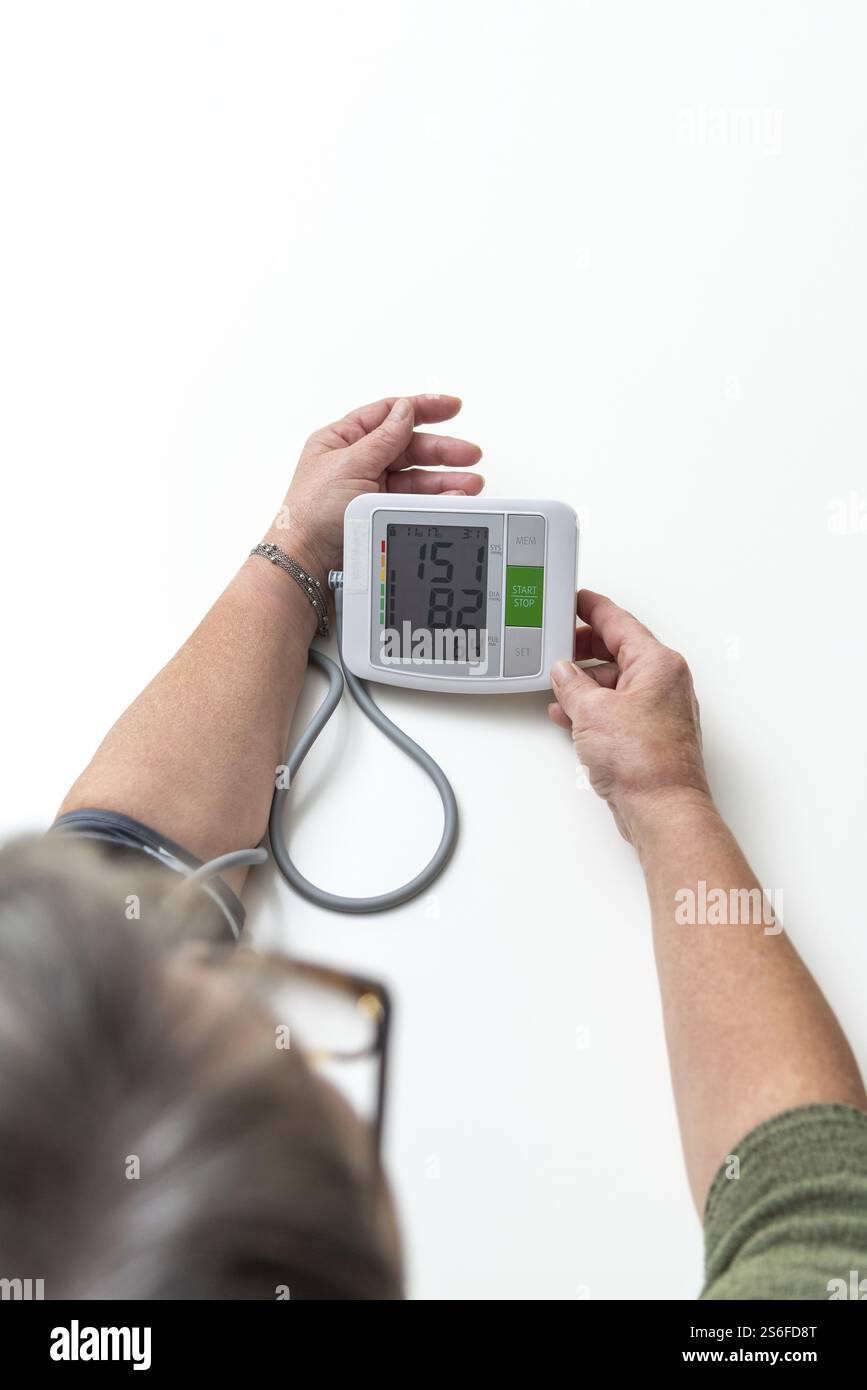 Senior adult woman measuring blood pressure with a portable monitor at ...