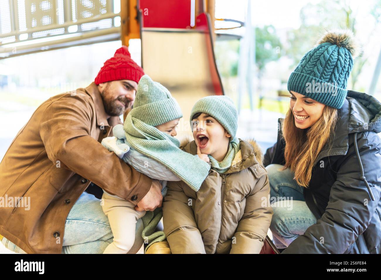 Family enjoying a winter day at the playground, bundled up in warm ...
