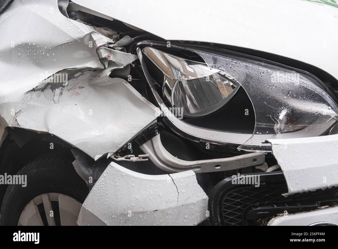 A heavily damaged white car after an accident. The front left mudguard ...