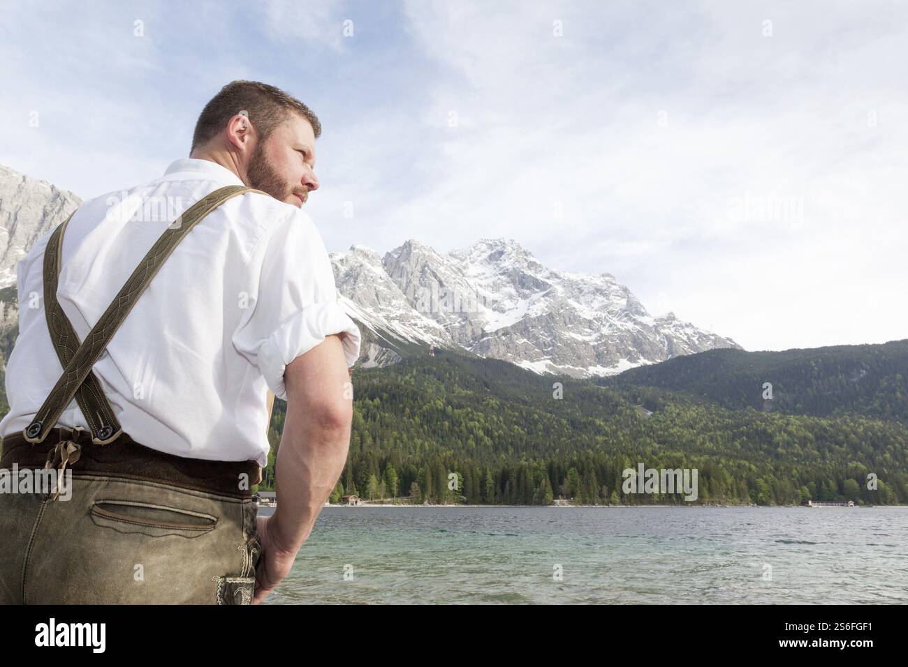 A traditional bavarian man at lake Eibsee with the Zugspitze mountain ...
