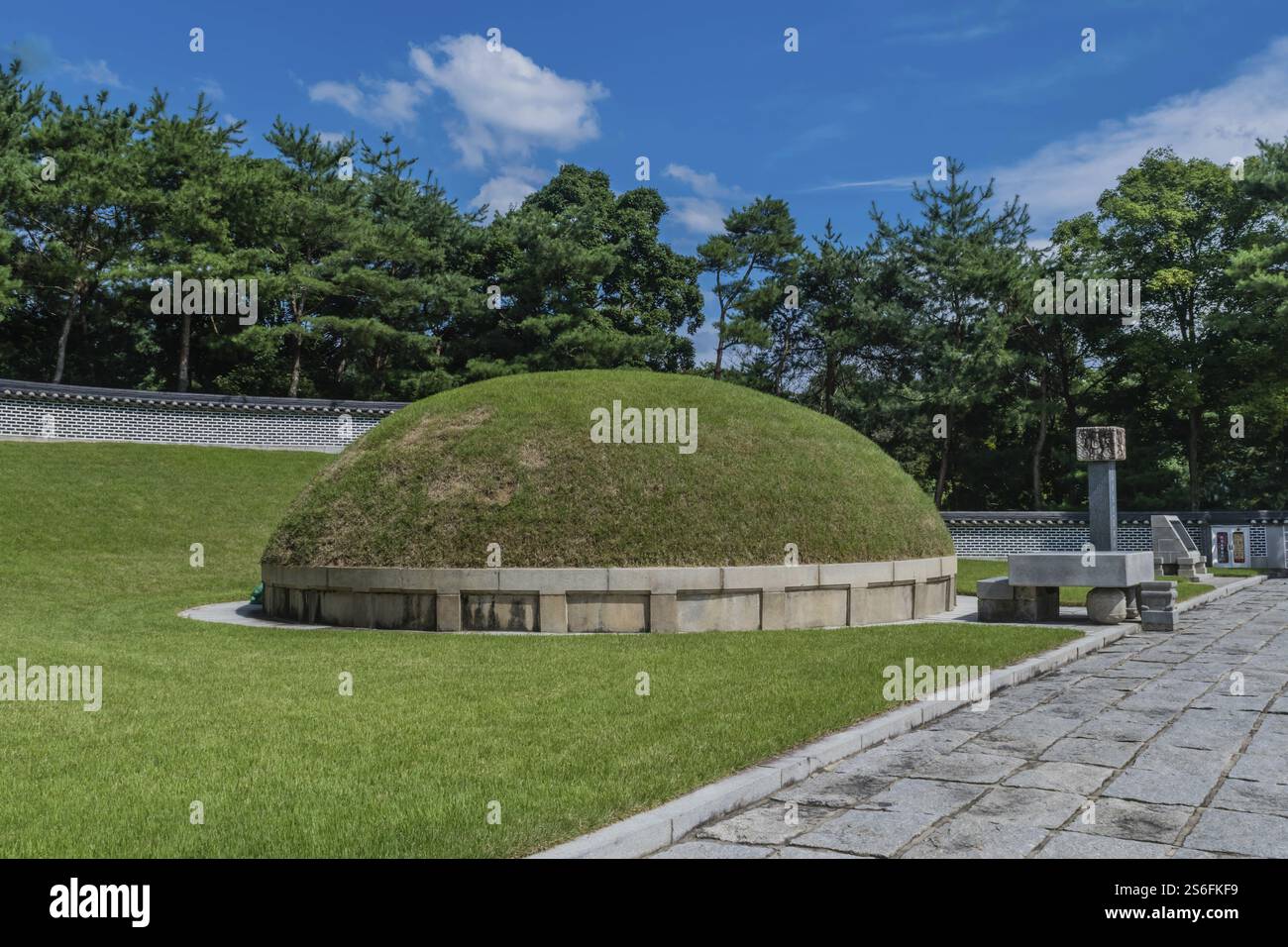 Ancient burial mound surrounded by lush grass and trees under a clear ...
