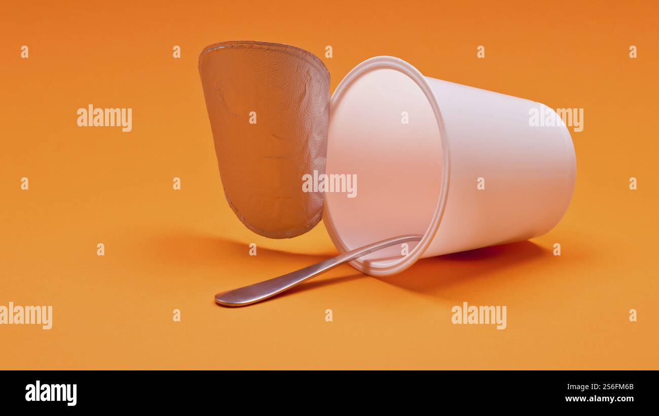 An empty clean yogurt cup with spoon on an orange background Stock ...