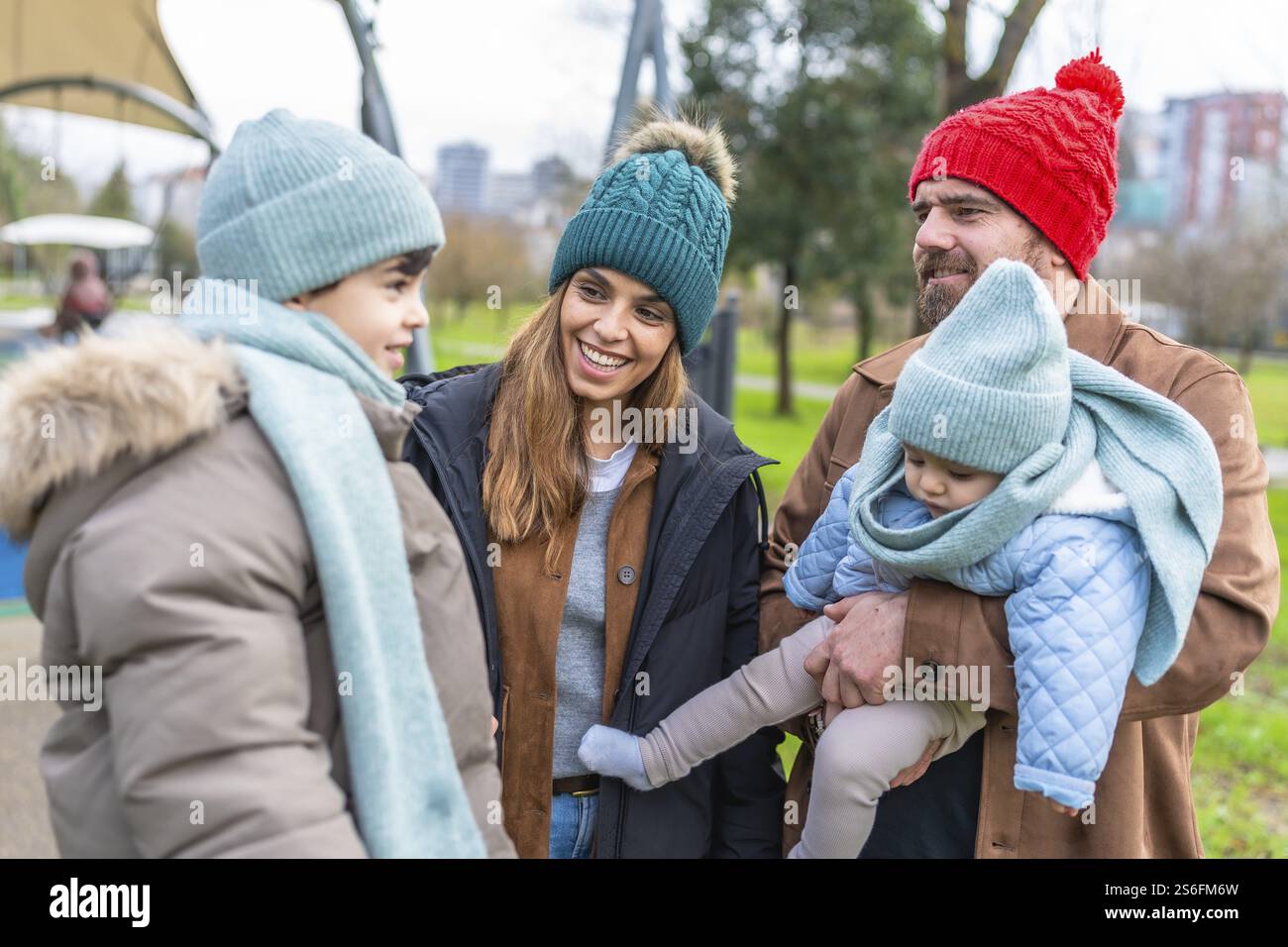 Smiling family wearing winter clothes spending time together at the ...