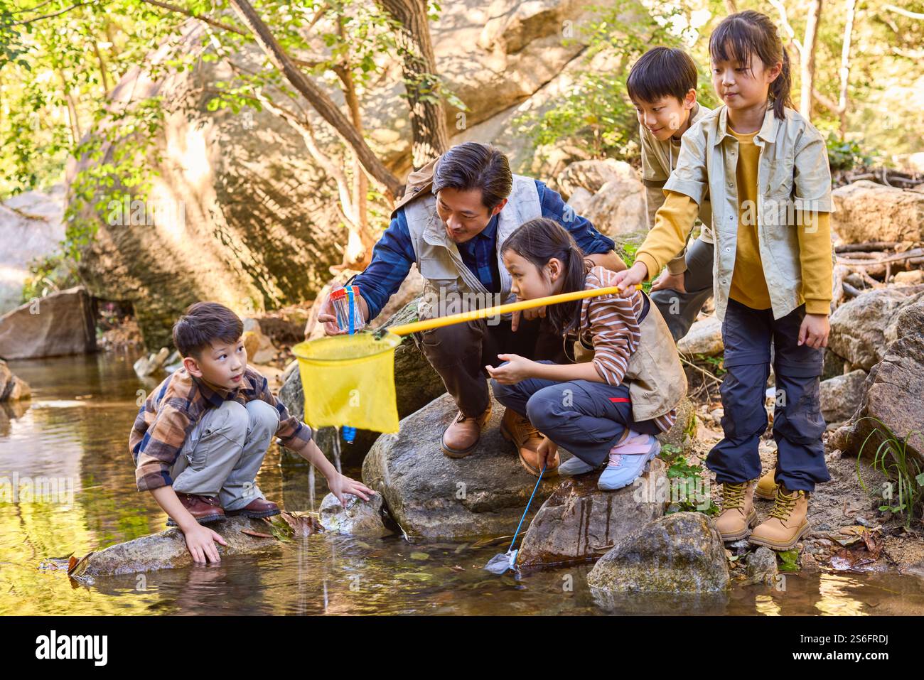 Teacher and kids having fun by the stream Stock Photo - Alamy