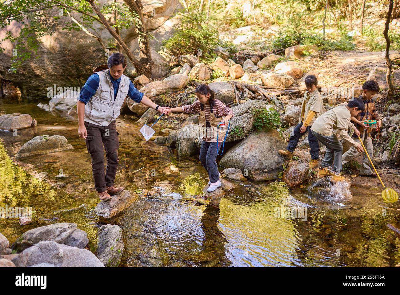 Teacher and kids having fun by the stream Stock Photo - Alamy