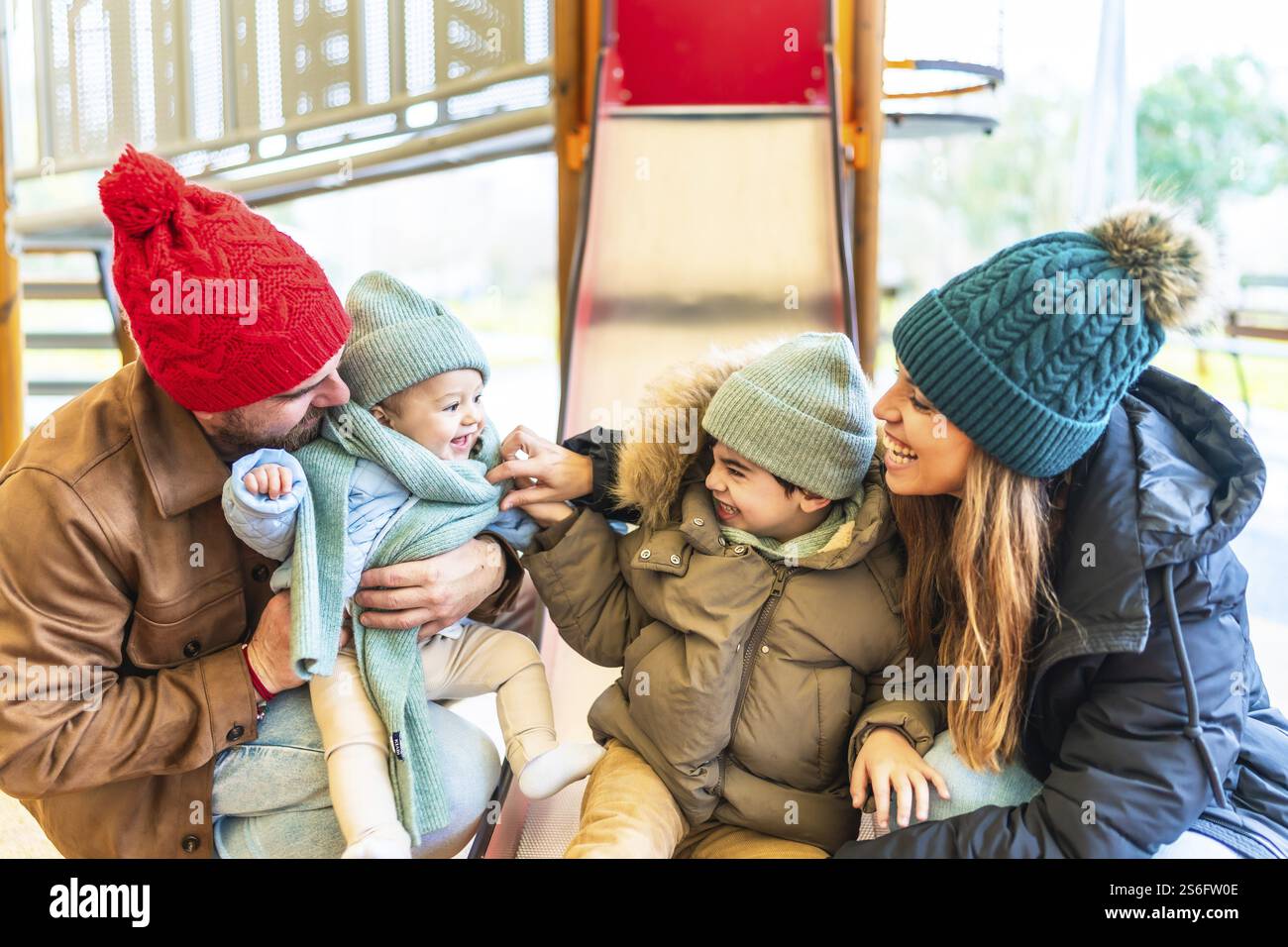 Cheerful family bundled in winter clothes enjoying quality time ...