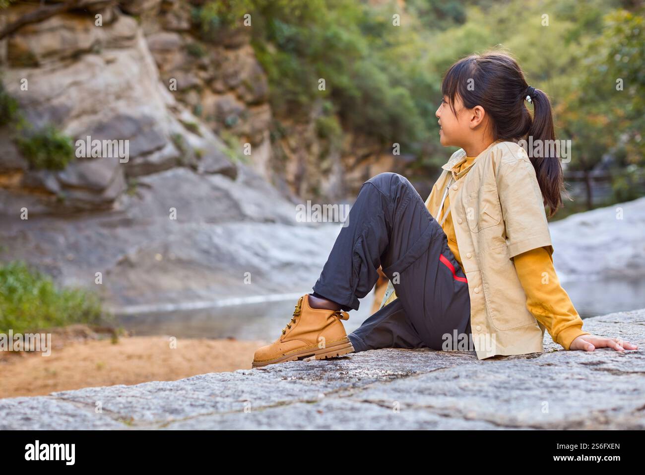 Happy girl sitting by the stream Stock Photo - Alamy