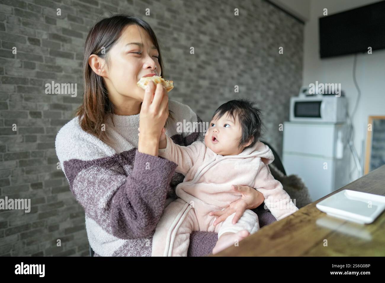 A Japanese mother in her 20s and a 6-month-old baby girl are in the room. Eating a burrito Stock ...