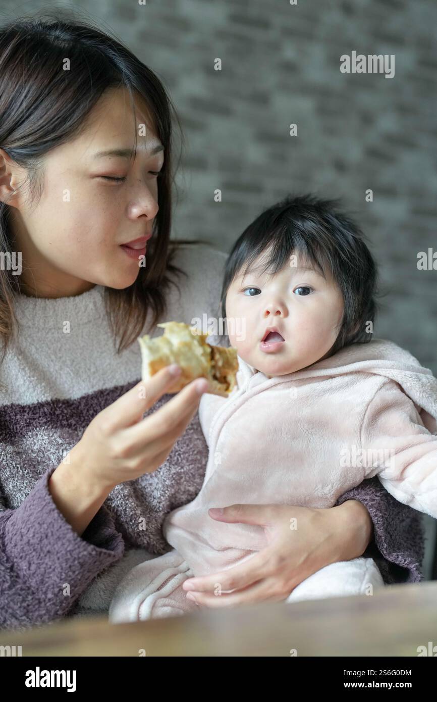 A Japanese mother in her 20s and a 6-month-old baby girl are in the room. Eating a burrito Stock ...