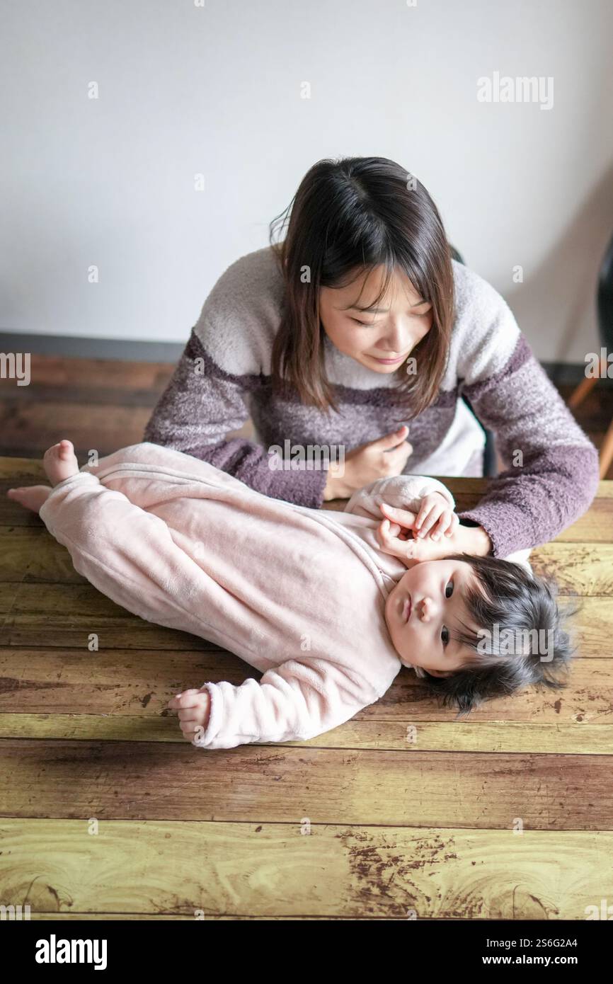 A Japanese mother in her 20s and a 6-month-old baby girl are in a room, sleeping on a desk Stock ...