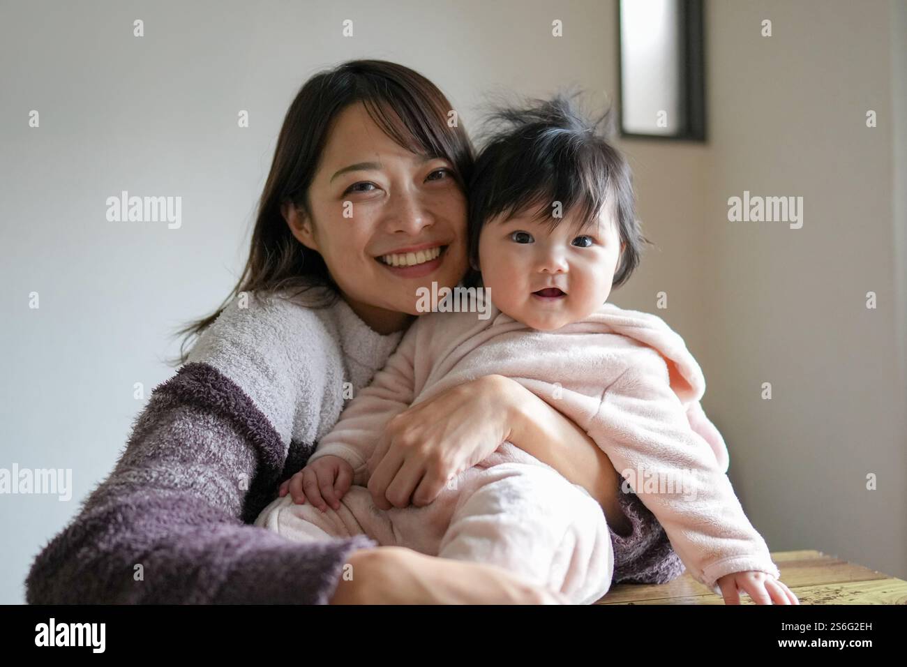 A Japanese mother in her 20s and a 6-month-old baby girl are in a room, sleeping on a desk Stock ...