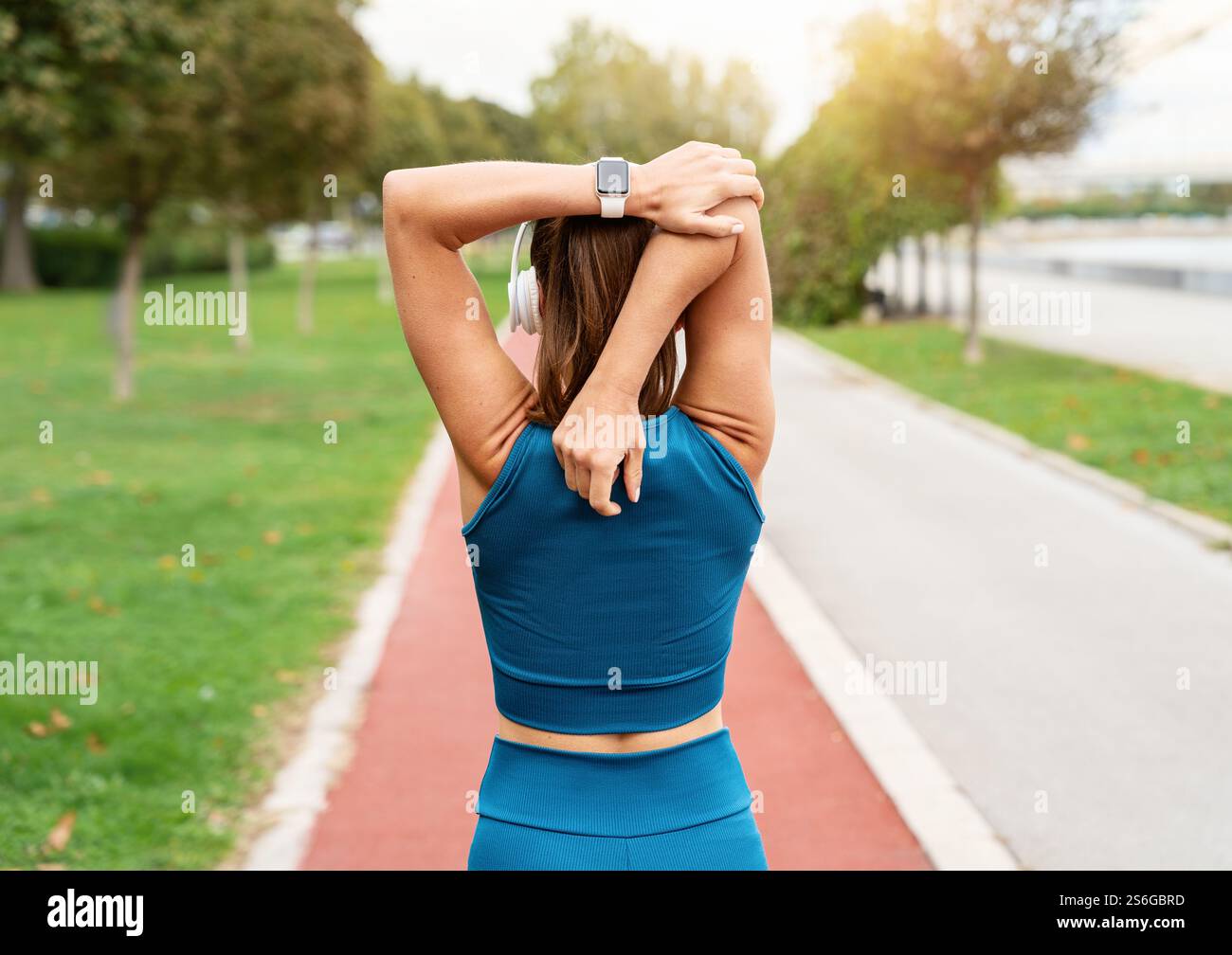 Rear view portrait of female athlete warming up on city street running ...