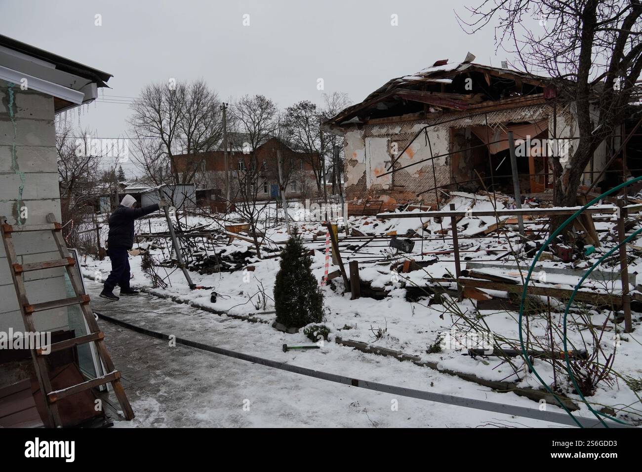 Kursk. 16th Jan, 2025. A man cleans debris around a damaged building ...