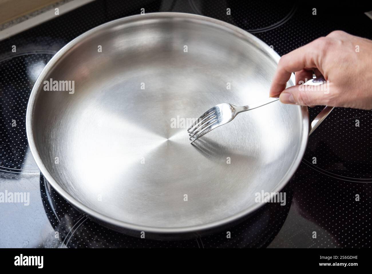 Hand Holding Fork Over Stainless Steel Frying Pan Stock Photo - Alamy