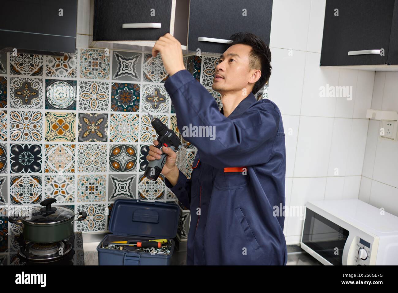 Handyman repairing the kitchen cabinet Stock Photo - Alamy