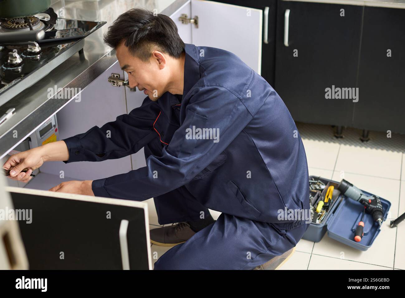 Handyman repairing the kitchen cabinet Stock Photo - Alamy