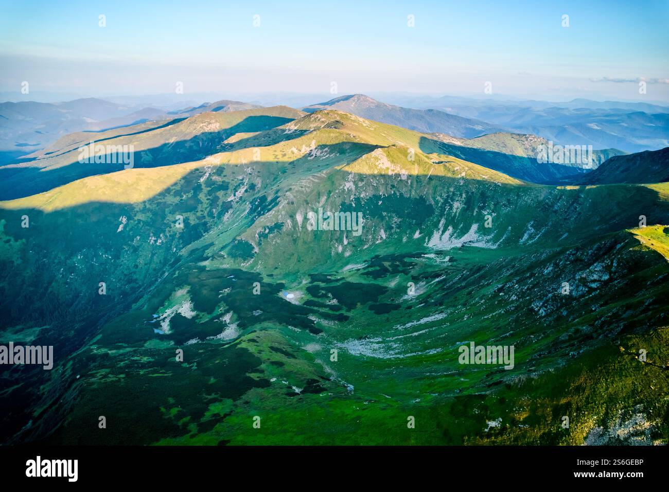 Aerial view of rugged mountain range with lush green slopes at sunset. Landscape showcases ...