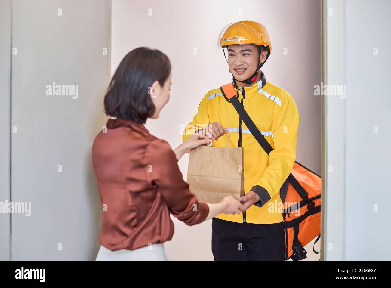 Delivery person delivering food to the lady Stock Photo - Alamy