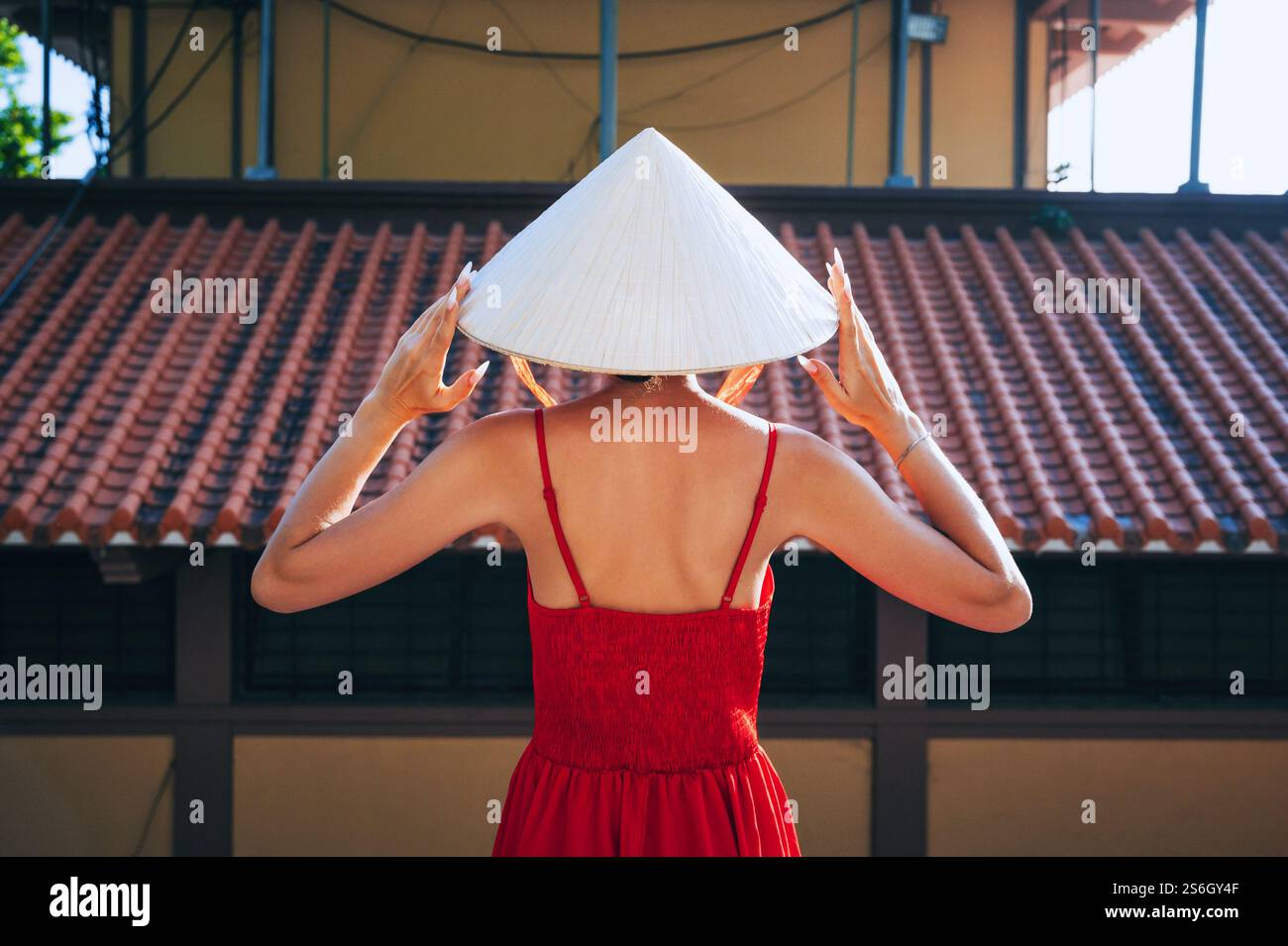 A tourist in a red dress and a traditional Vietnamese hat against the ...