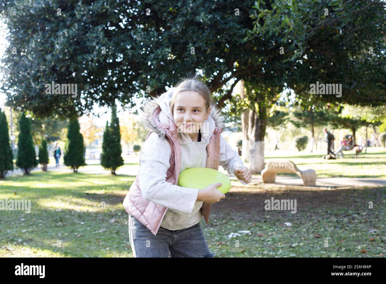 Cute happy girl child playing flying disc in a sunny, green outdoor ...