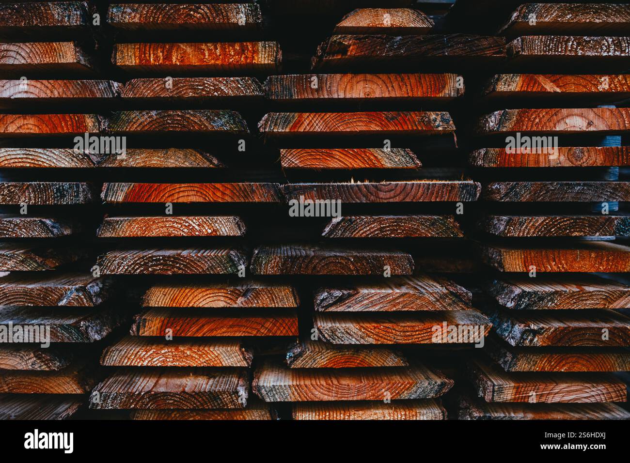 Stacked cut wooden planks with visible grain patterns and rich t Stock ...