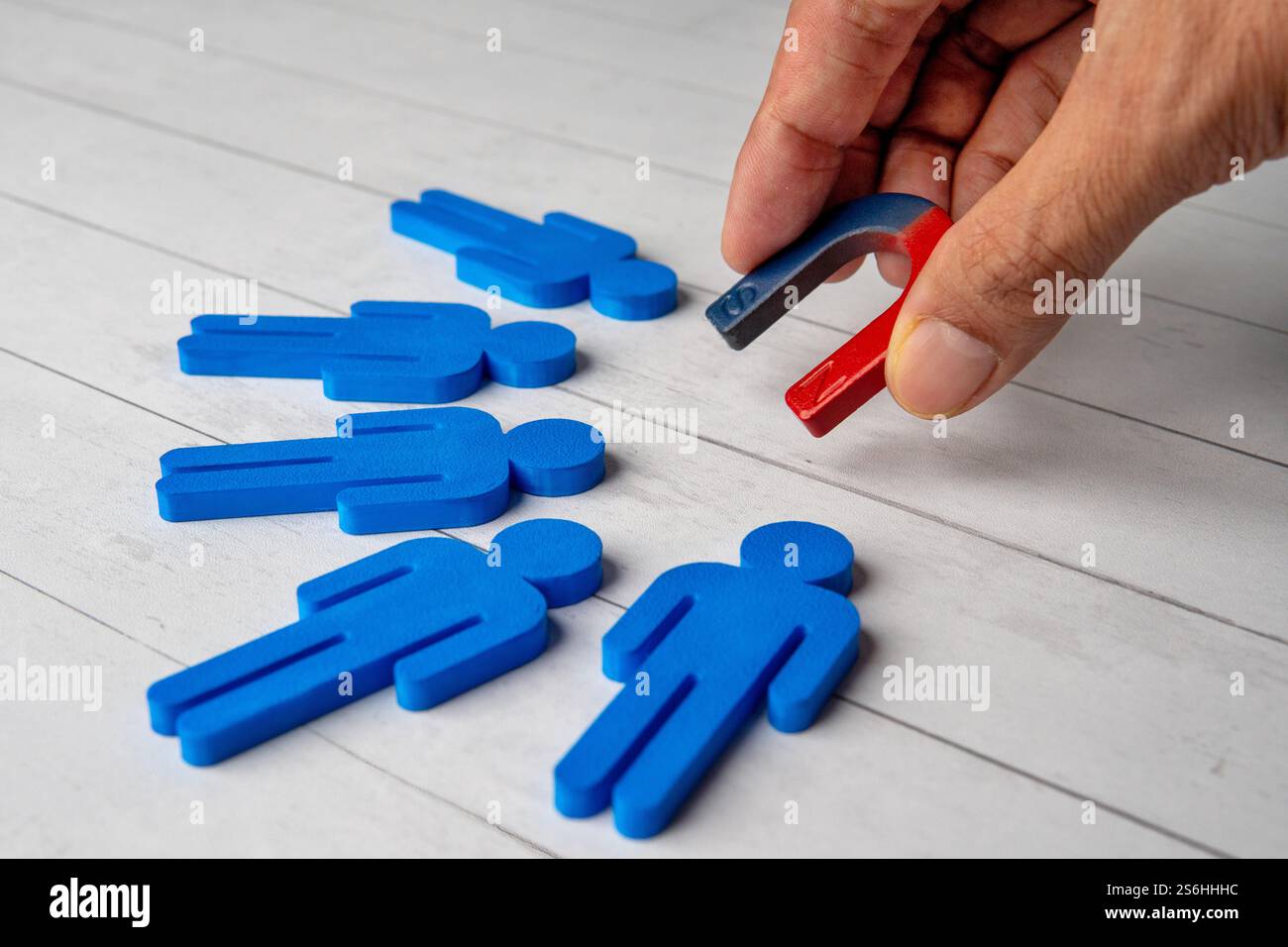 Hand holding a magnet attracts a blue figures. Customer retention ...