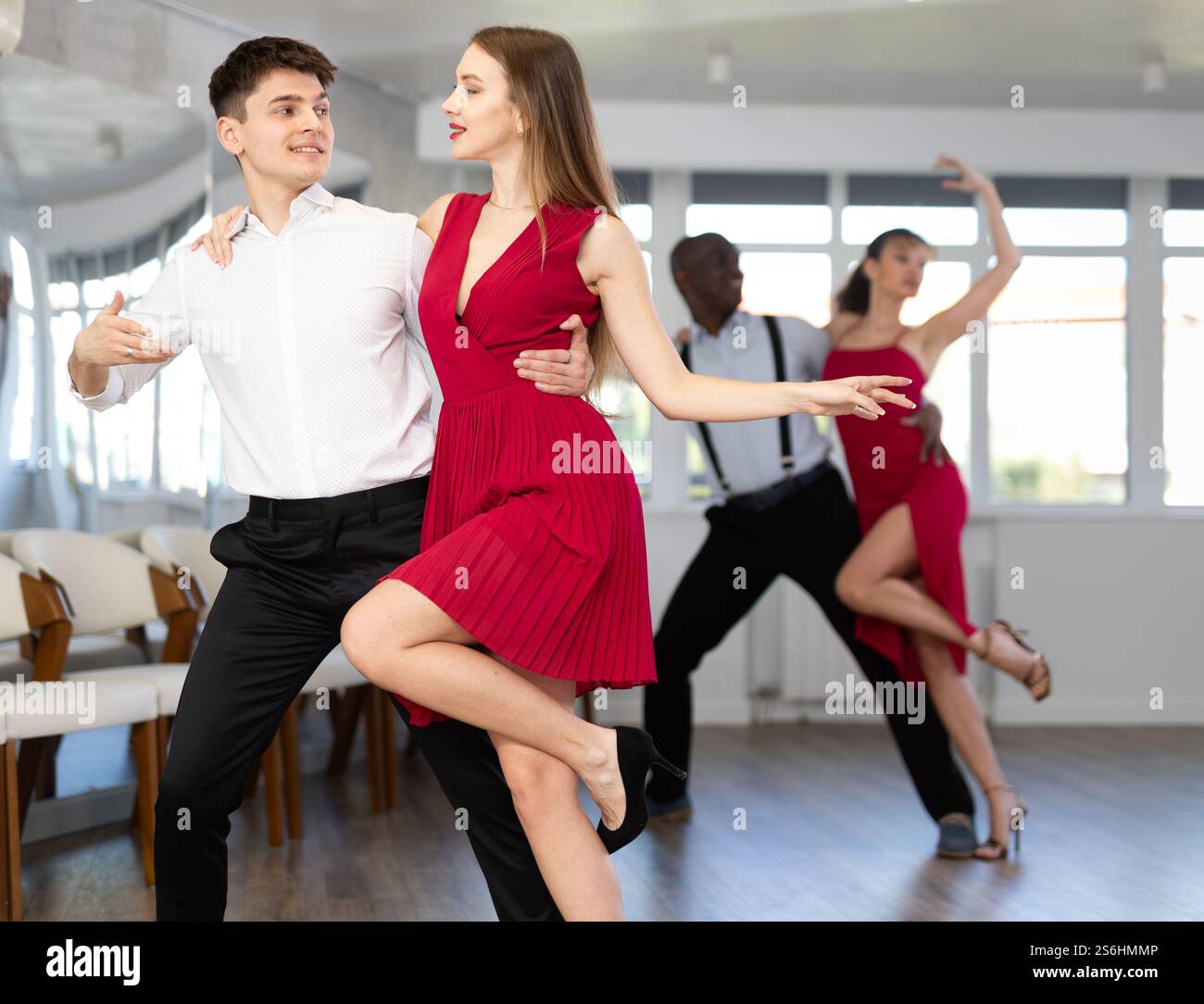 Young man and girl dancing tango in couple during lesson at studio ...