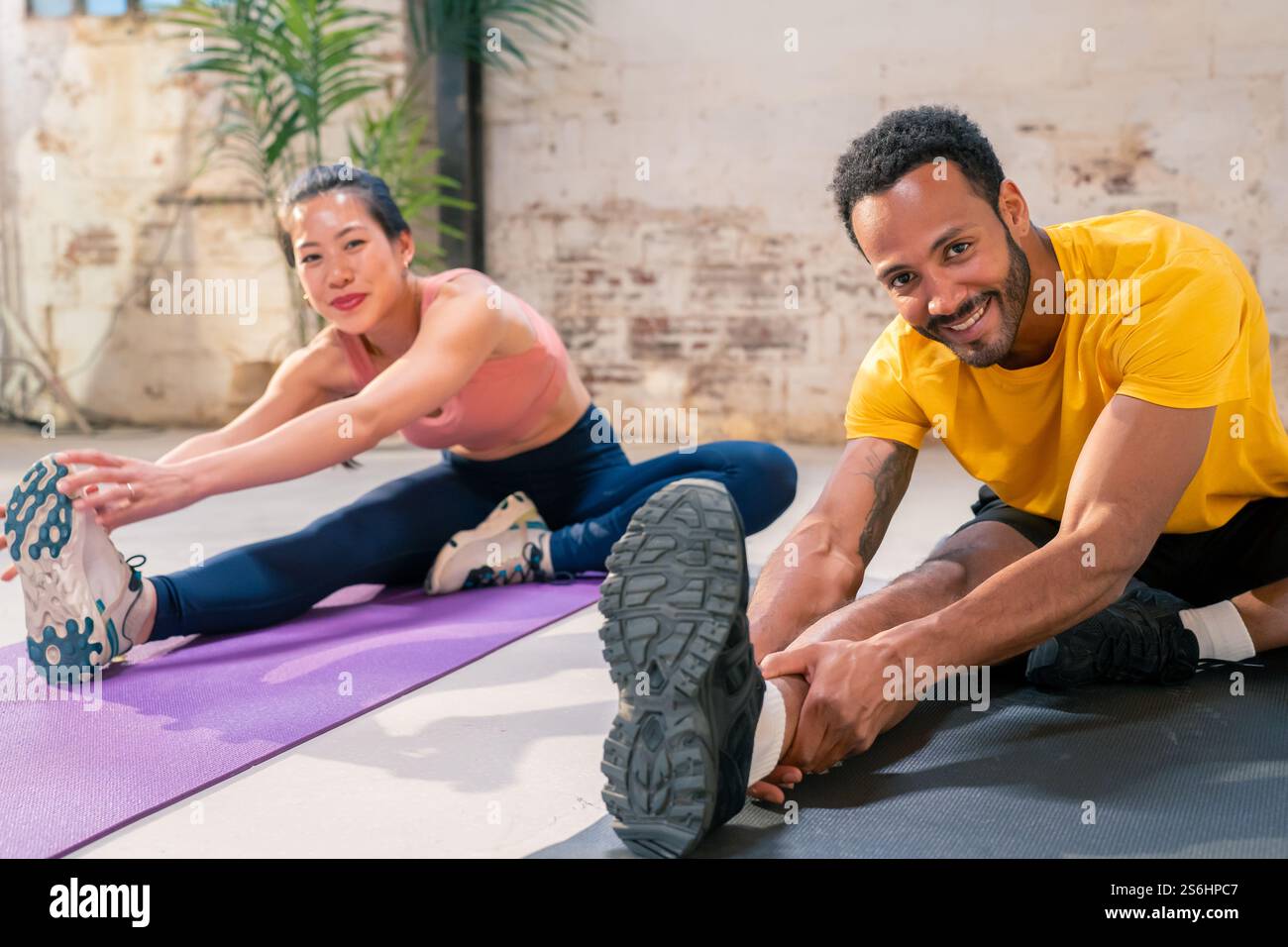 Mixed race sporty man and girl doing exercise together in a industrial ...
