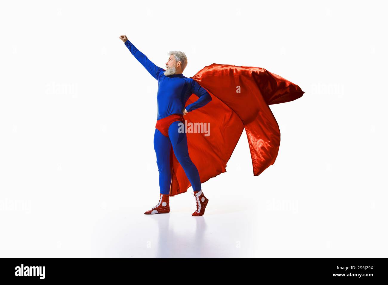 Grey-haired man in superhero costume with red cape waving, strikes ...