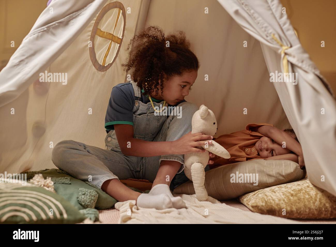 Young Black girl comforting sad little brother by showing teddy bear ...