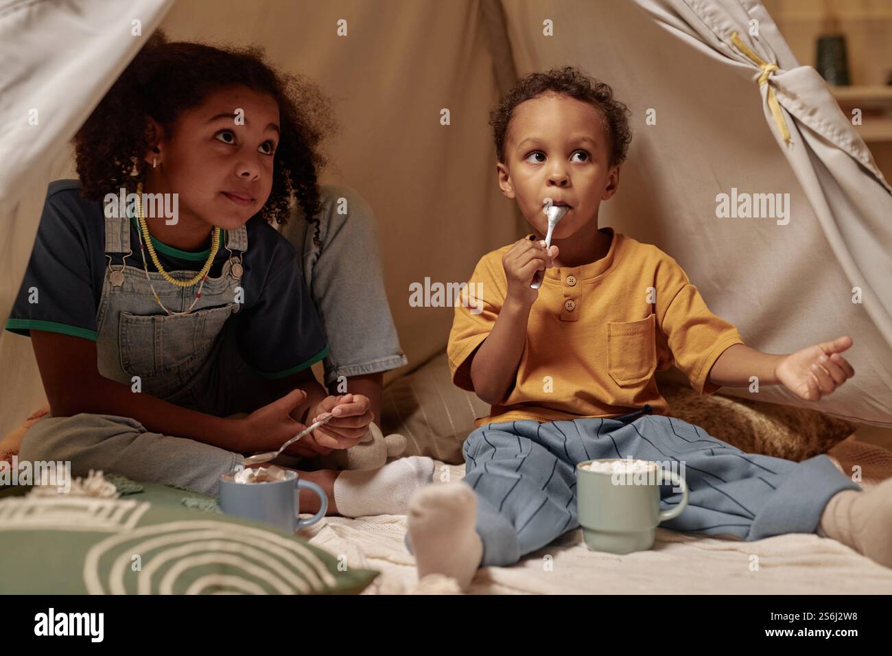 Two African American brother and sister of preschool age sitting inside ...