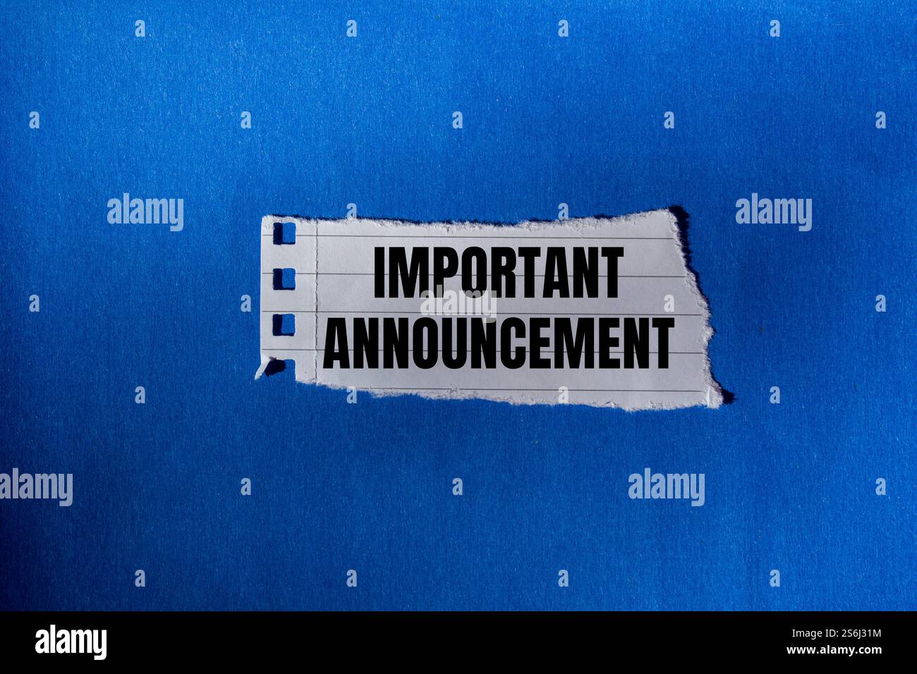 Important announcement message written on ripped torn paper piece with blue background ...