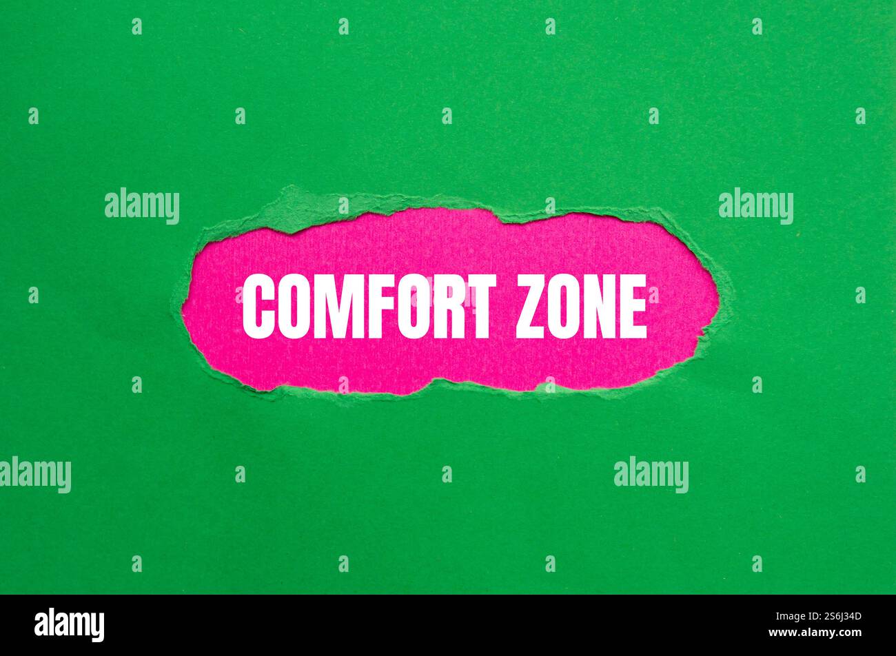 Comfort zone message written on ripped torn green paper with pink background. Conceptual comfort ...