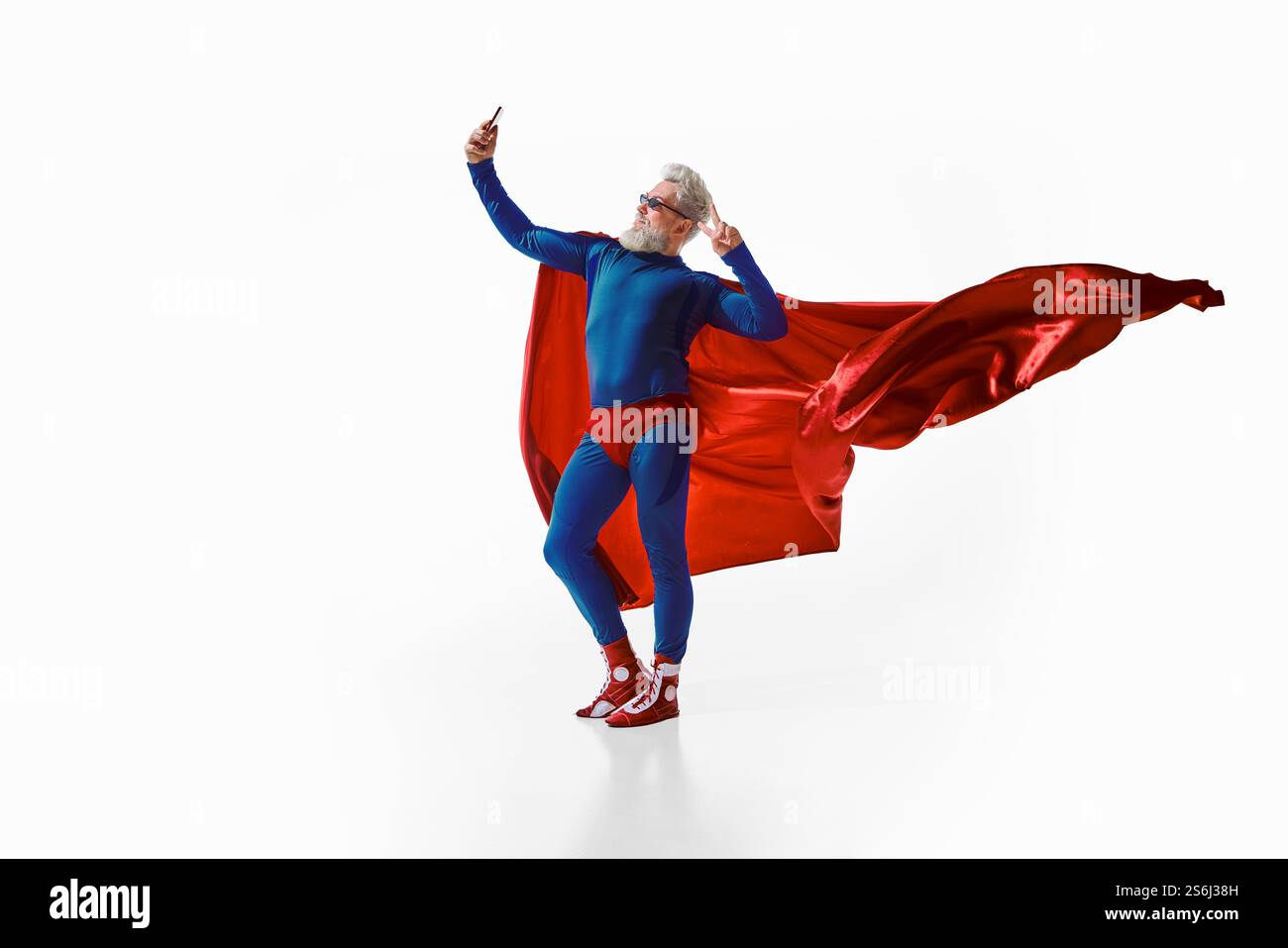 Relaxed, grey-haired man in superhero costume with red cape and ...