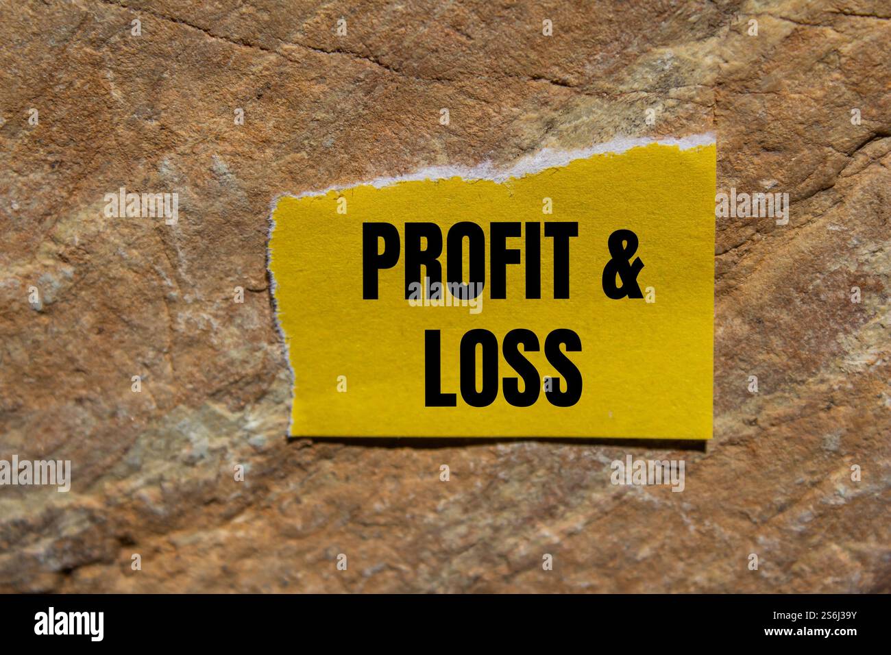 Profit and loss message written on ripped torn yellow paper piece with ...