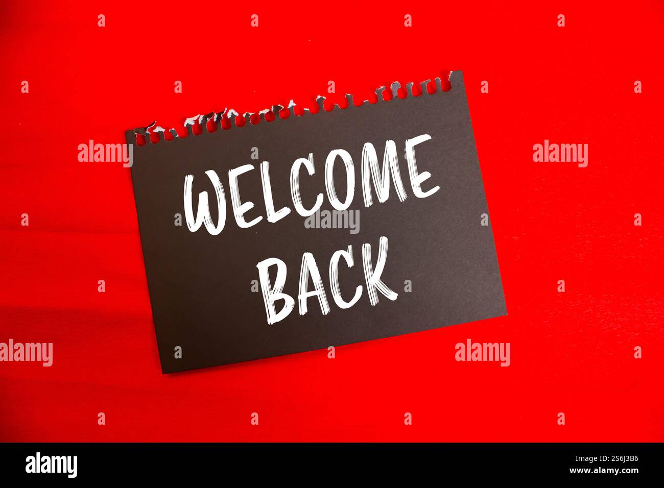Welcome back message written on black paper with red background ...