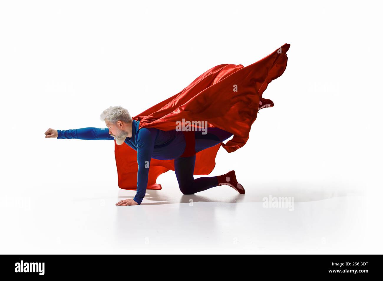 Grey-haired bearded young man in superhero costume with red cape ...