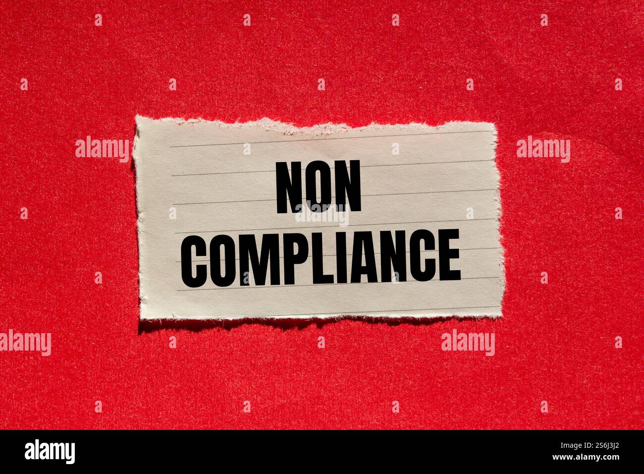 Non compliance message written on ripped torn paper piece with red background. Conceptual non ...