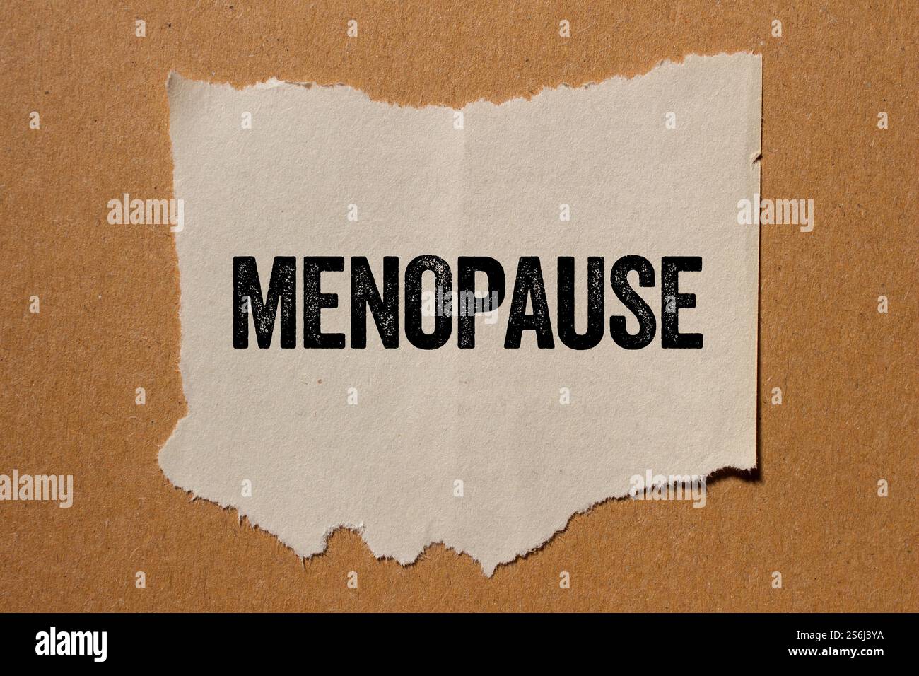 Menopause message written on ripped torn paper piece on brown background. Conceptual menopause ...