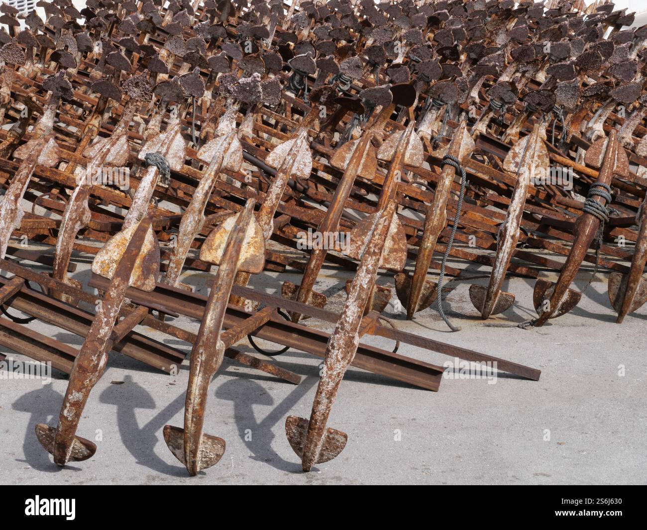 Rusty ship anchors are placed next to each other in the fishing port of ...