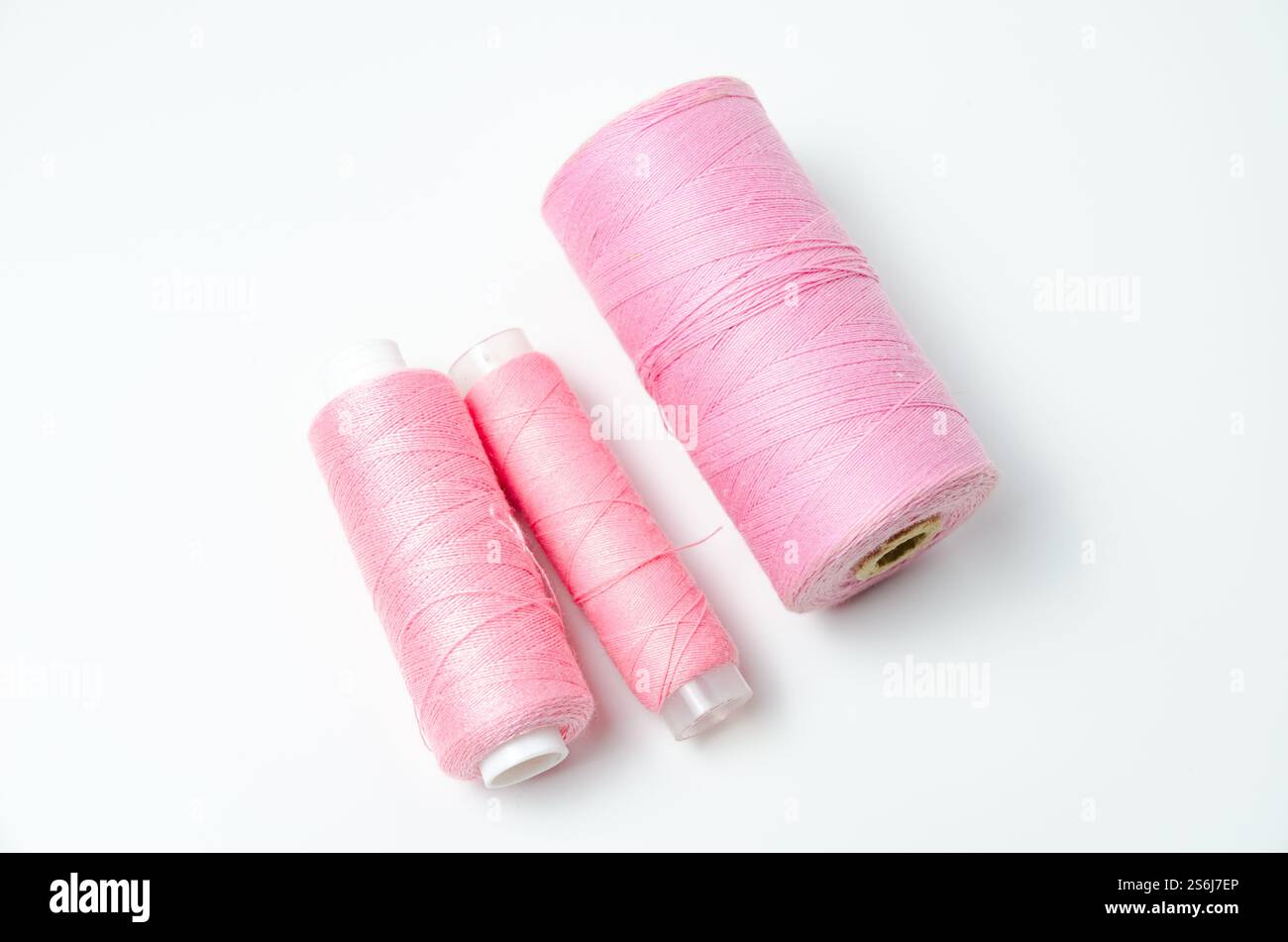 Pink thread spools on white background Stock Photo - Alamy