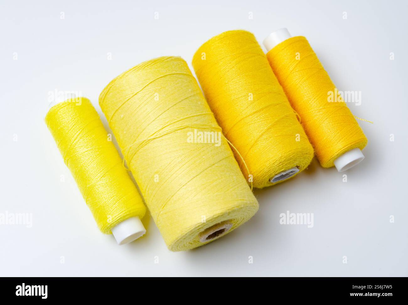 Yellow thread spools on white background Stock Photo - Alamy